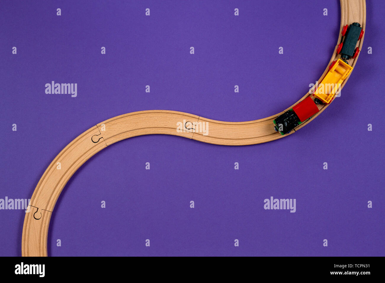 Toy train and wooden rails on purple violet background Stock Photo - Alamy