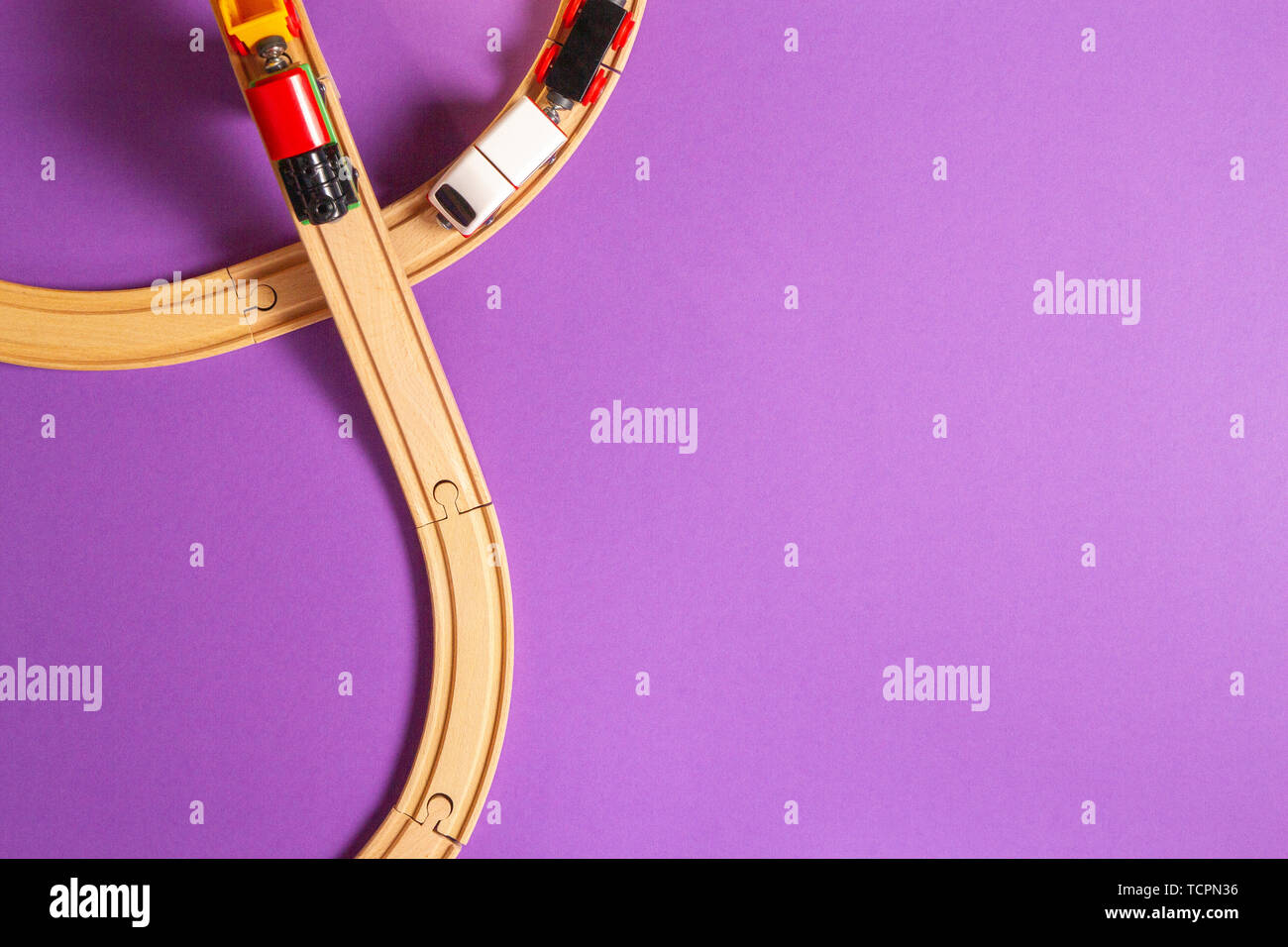 Toy train and wooden rails on purple violet background Stock Photo - Alamy
