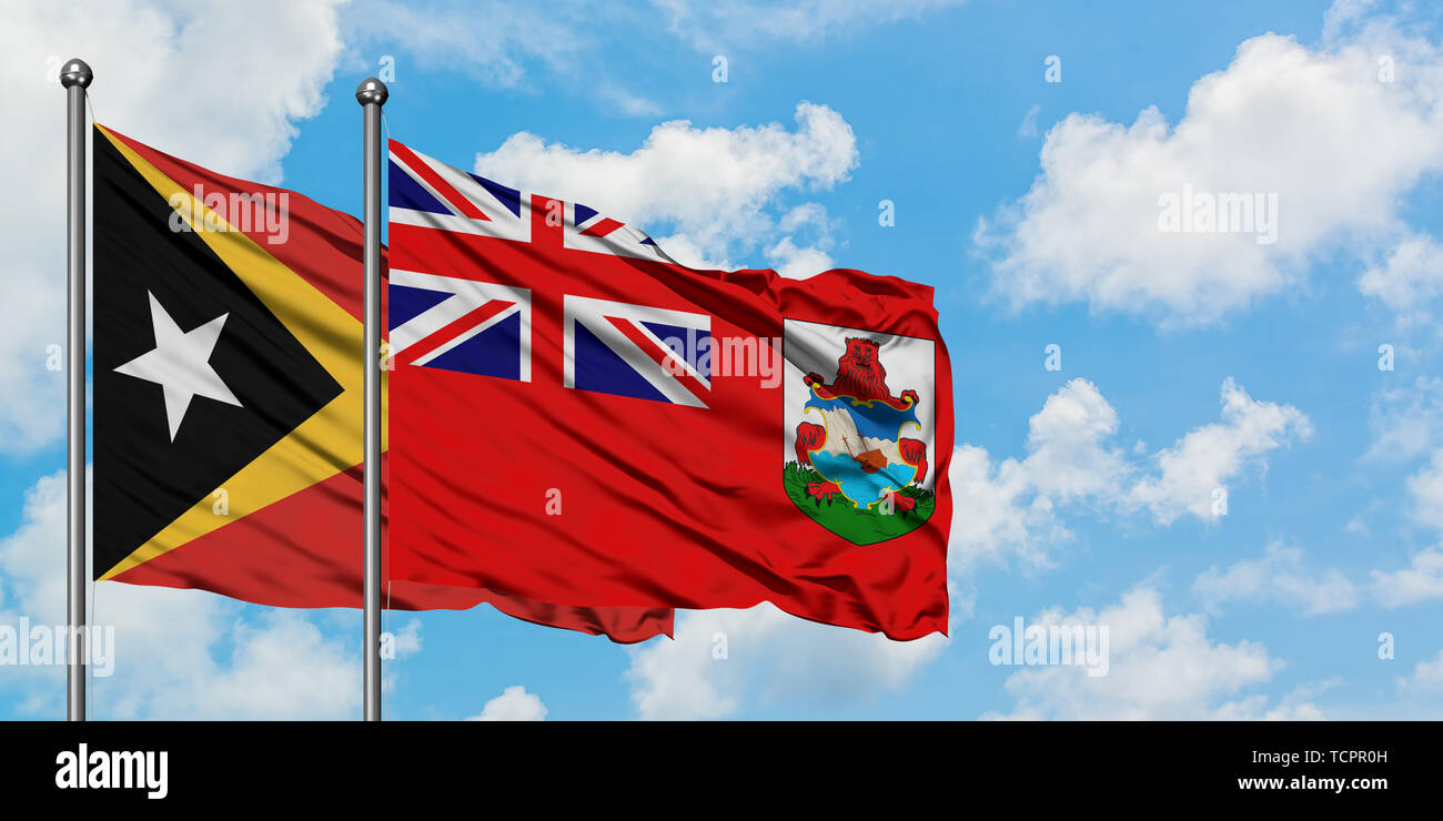 East Timor and Bermuda flag waving in the wind against white cloudy ...