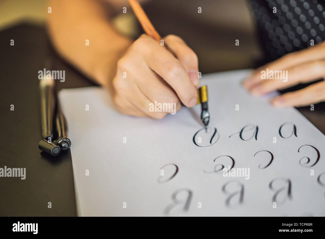 Calligrapher Young Woman writes phrase on white paper. Inscribing ...