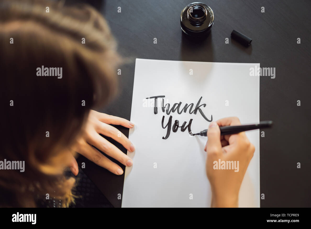 Thank you. Calligrapher Young Woman writes phrase on white paper ...