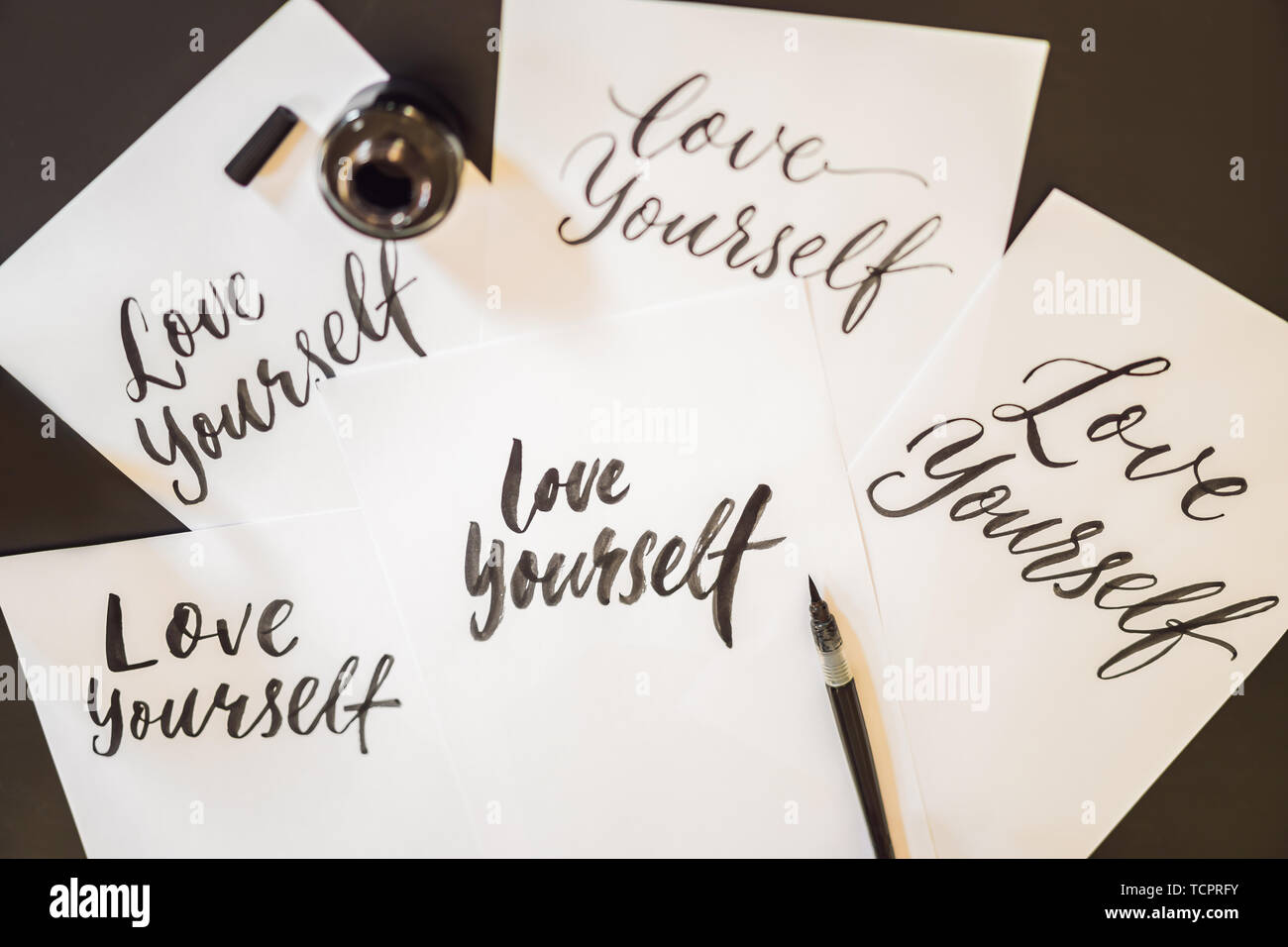 Love yourself. Calligrapher Young Woman writes phrase on white paper ...