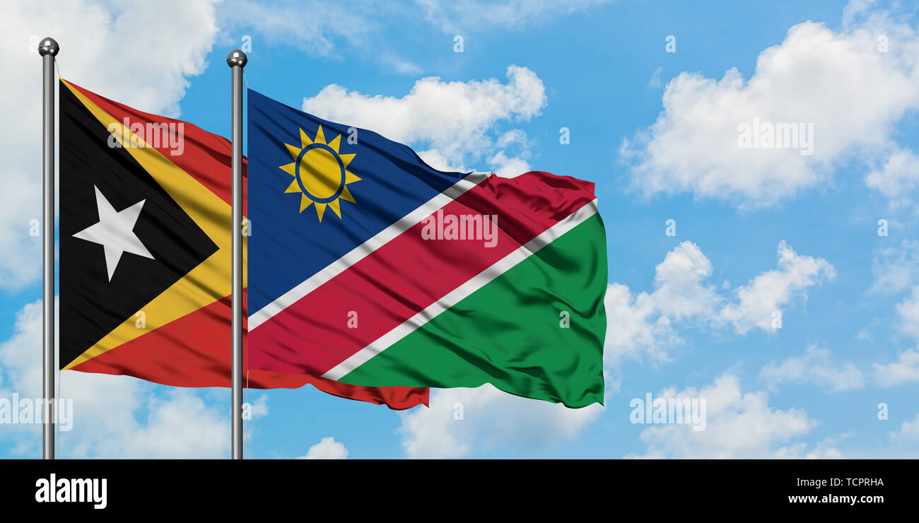 East Timor and Namibia flag waving in the wind against white cloudy ...