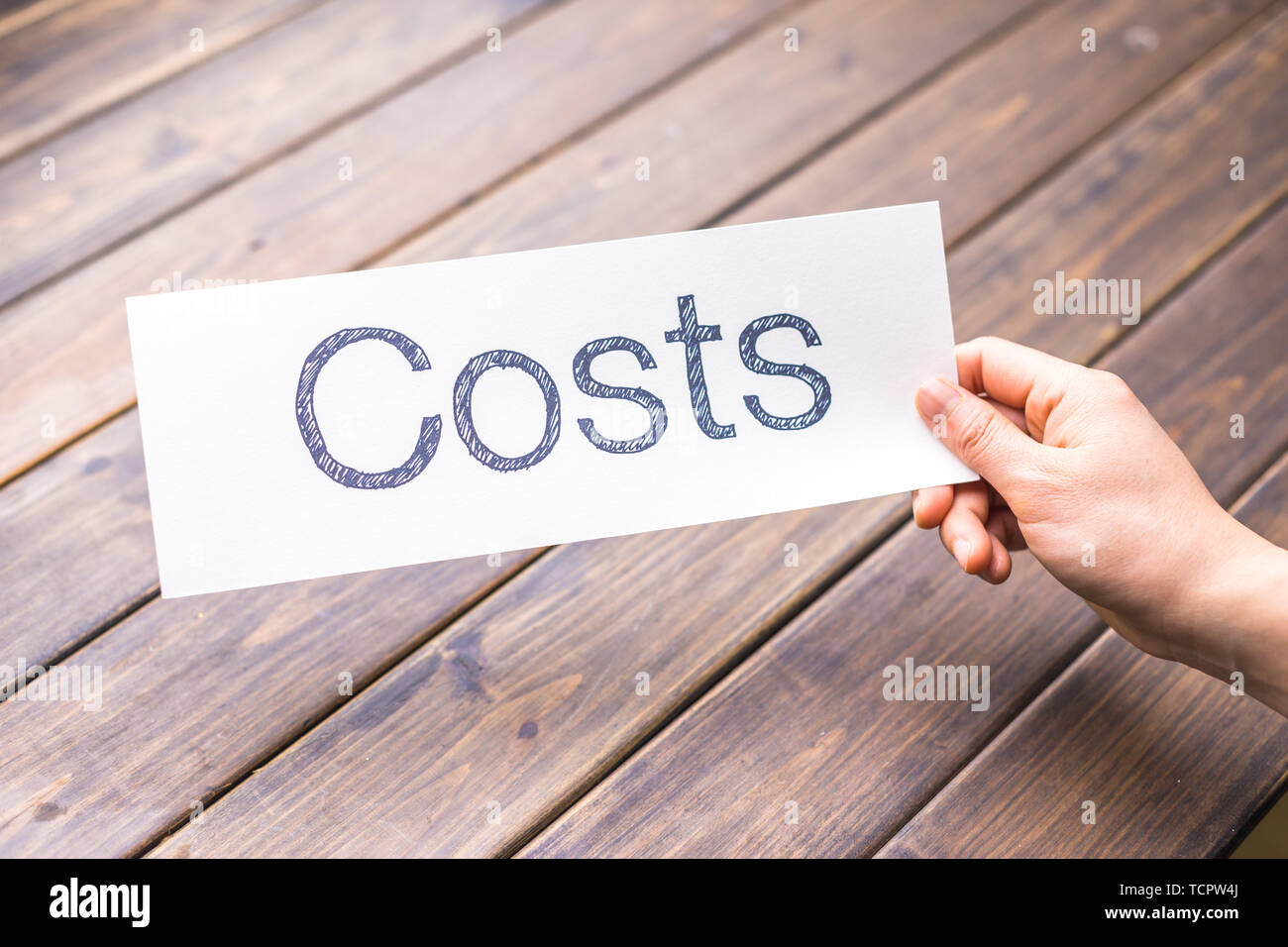 Hand hold white paper with word cost Stock Photo - Alamy