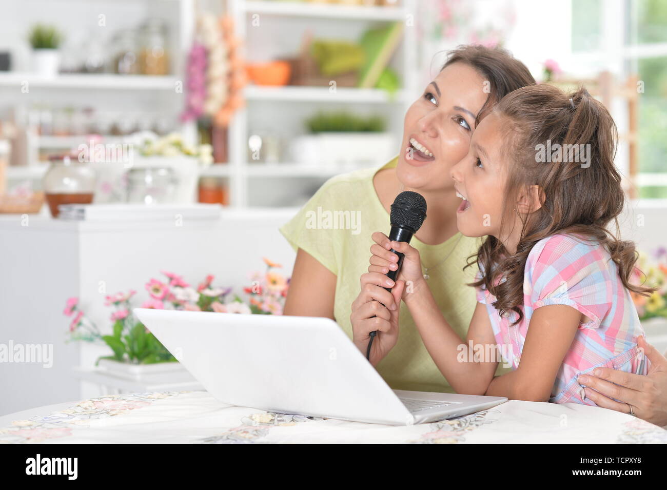 Portrait of mother and daughter singing karaoke with microphone ...
