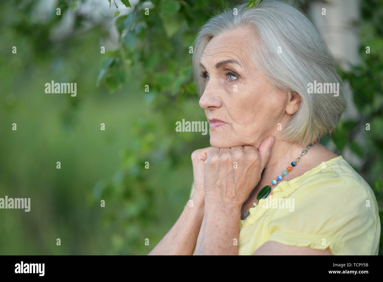 Portrait of sad senior beautiful woman in spring park Stock Photo - Alamy