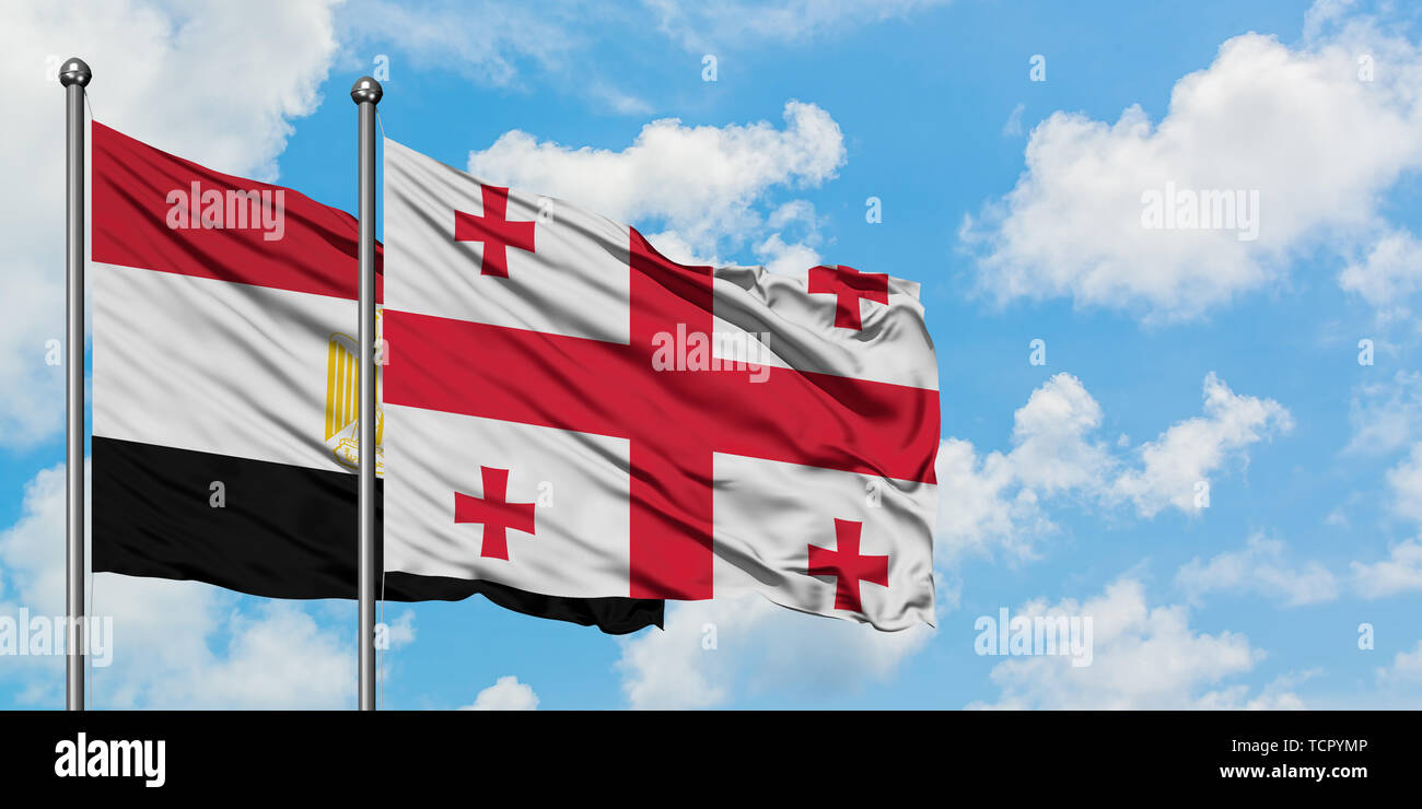 Egypt and Georgia flag waving in the wind against white cloudy blue sky ...