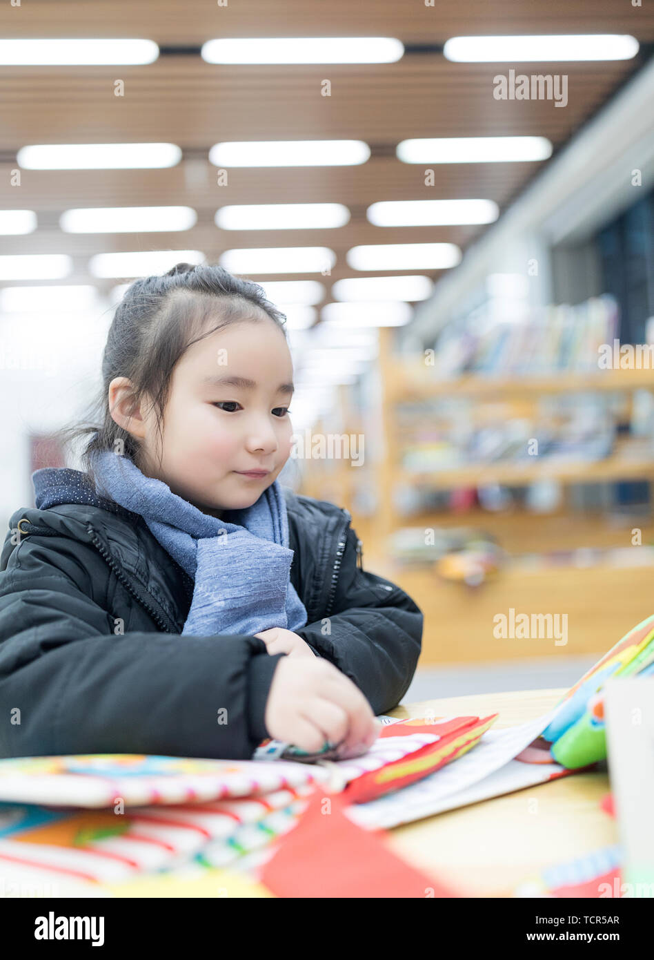 Little Asian girl reading in the library Stock Photo - Alamy