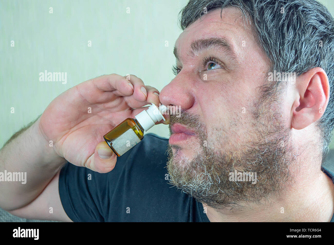 man with runny nose treats nose with nasal spra Stock Photo - Alamy