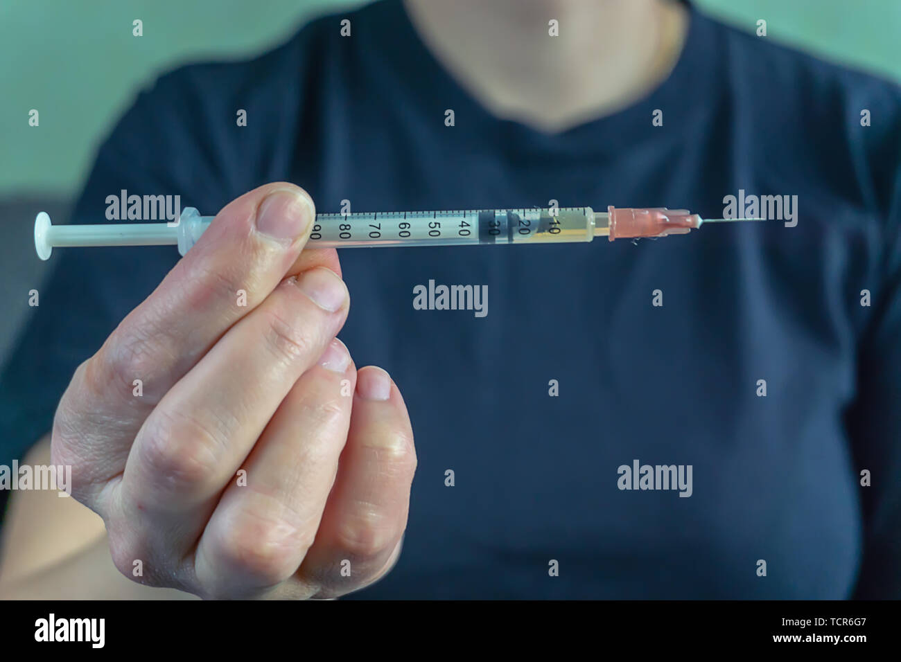 young drug addict with a syringe in her hand makes herself an injection ...