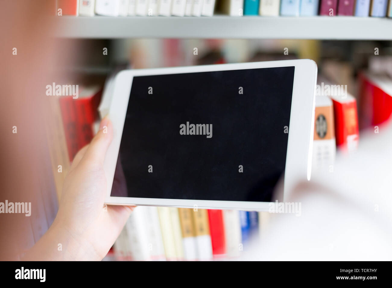close up of hand touching tablet in library Stock Photo - Alamy