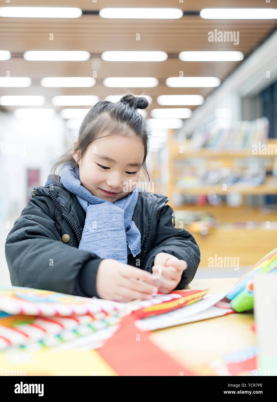 Little Asian girl reading in the library Stock Photo - Alamy