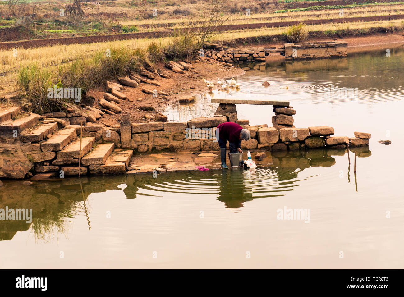 People wash clothes by the pond at the entrance of the village ...