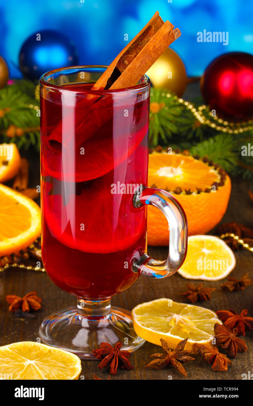 Fragrant mulled wine in glass with spices and oranges around on wooden ...