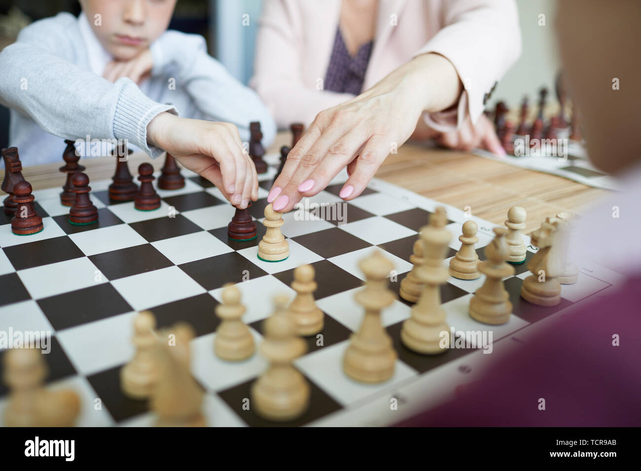 Hand of teacher moving chess figures and explaining how to react to ...