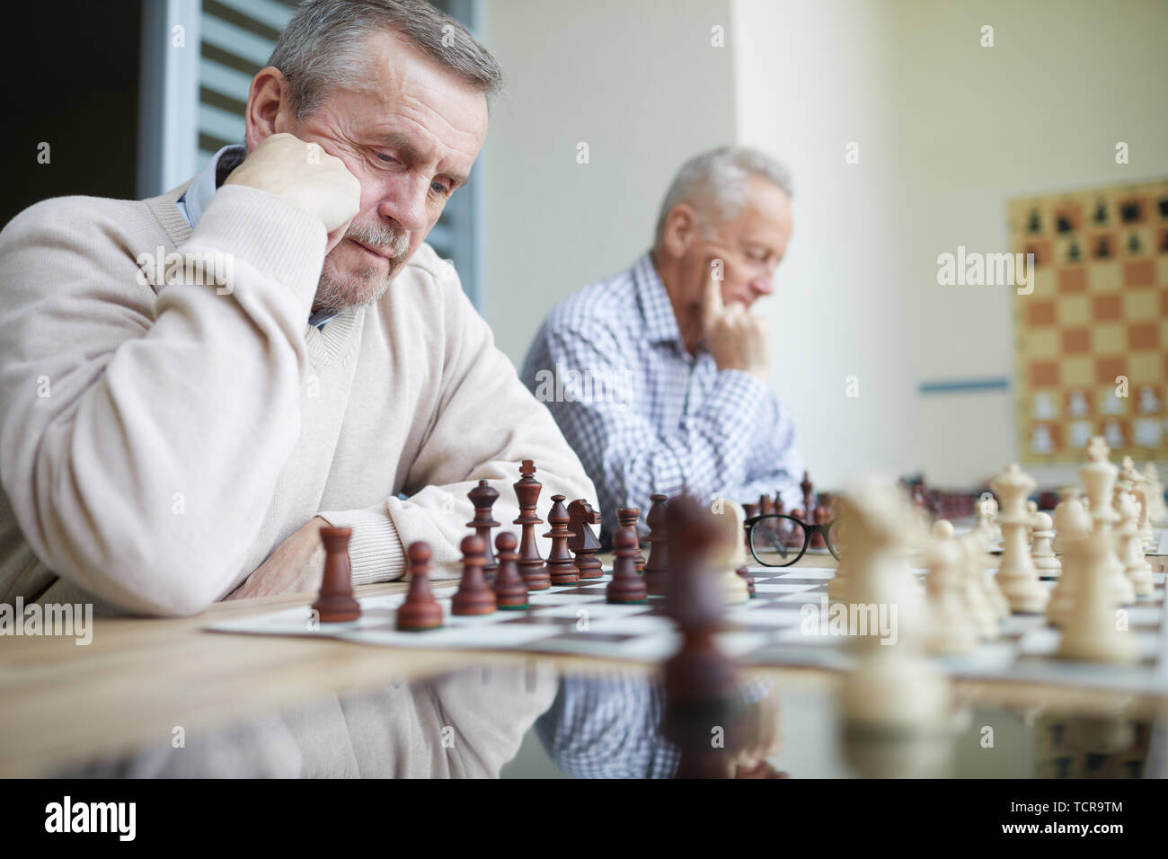 Two experienced aged chess players with silver hair trying to solve ...