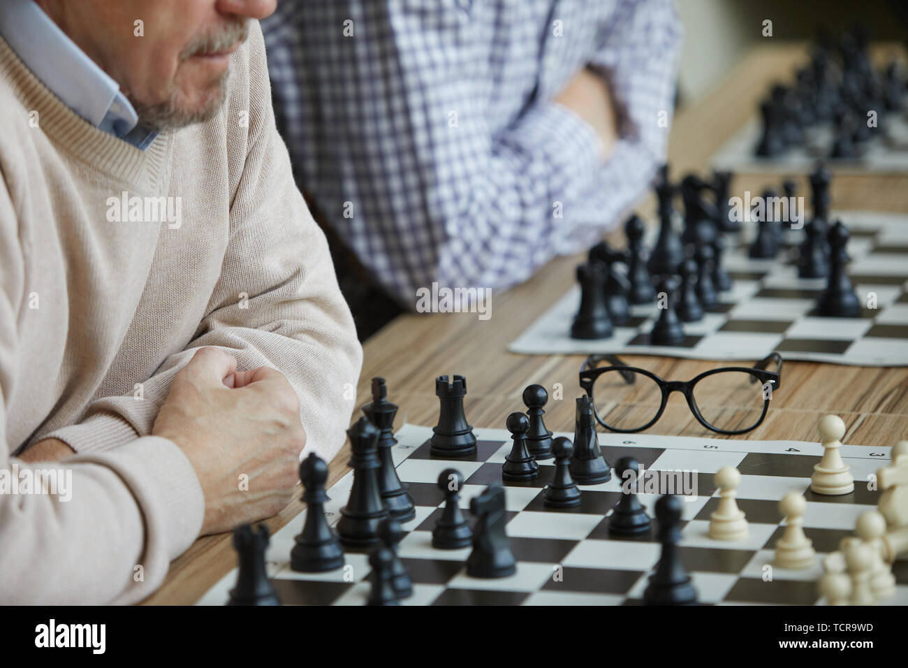 Two serious chess players sitting in row with crossed hands during ...