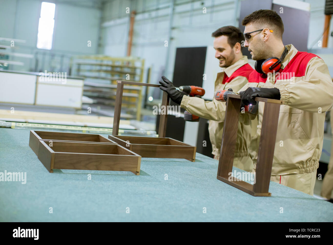 Two handsome young workers assembling furniture in the factory Stock ...