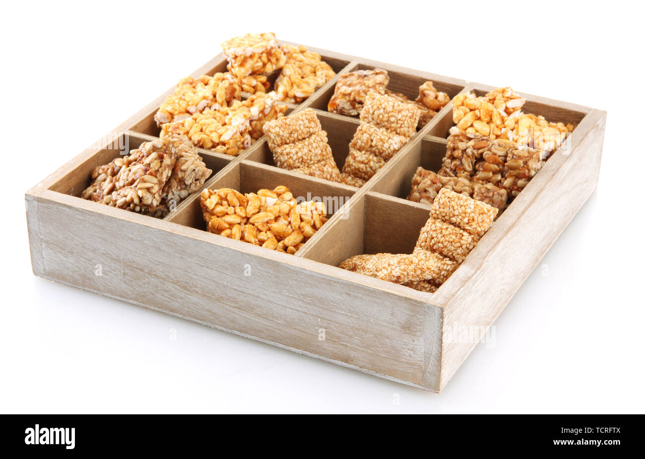tasty sweets (kozinaki)in wooden crate, isolated on white Stock Photo ...