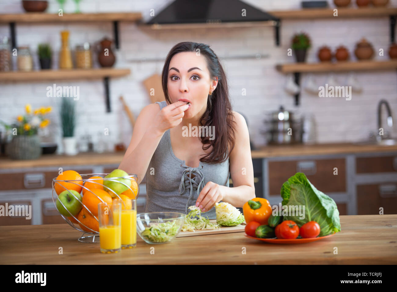 A hungry woman takes her hands and eats vegetables, stuffing them in ...