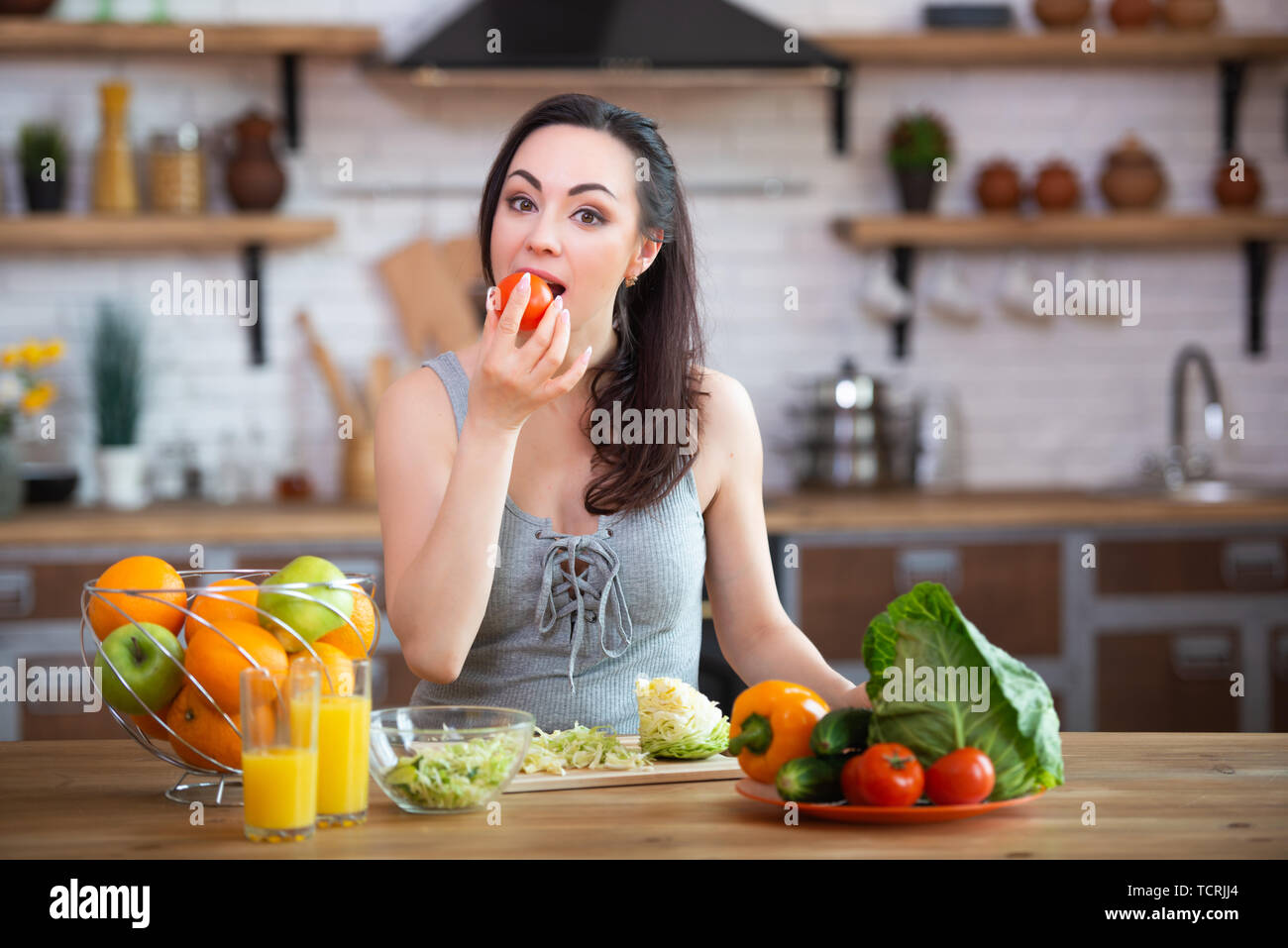 A hungry woman takes her hands and eats vegetables, stuffing them in ...