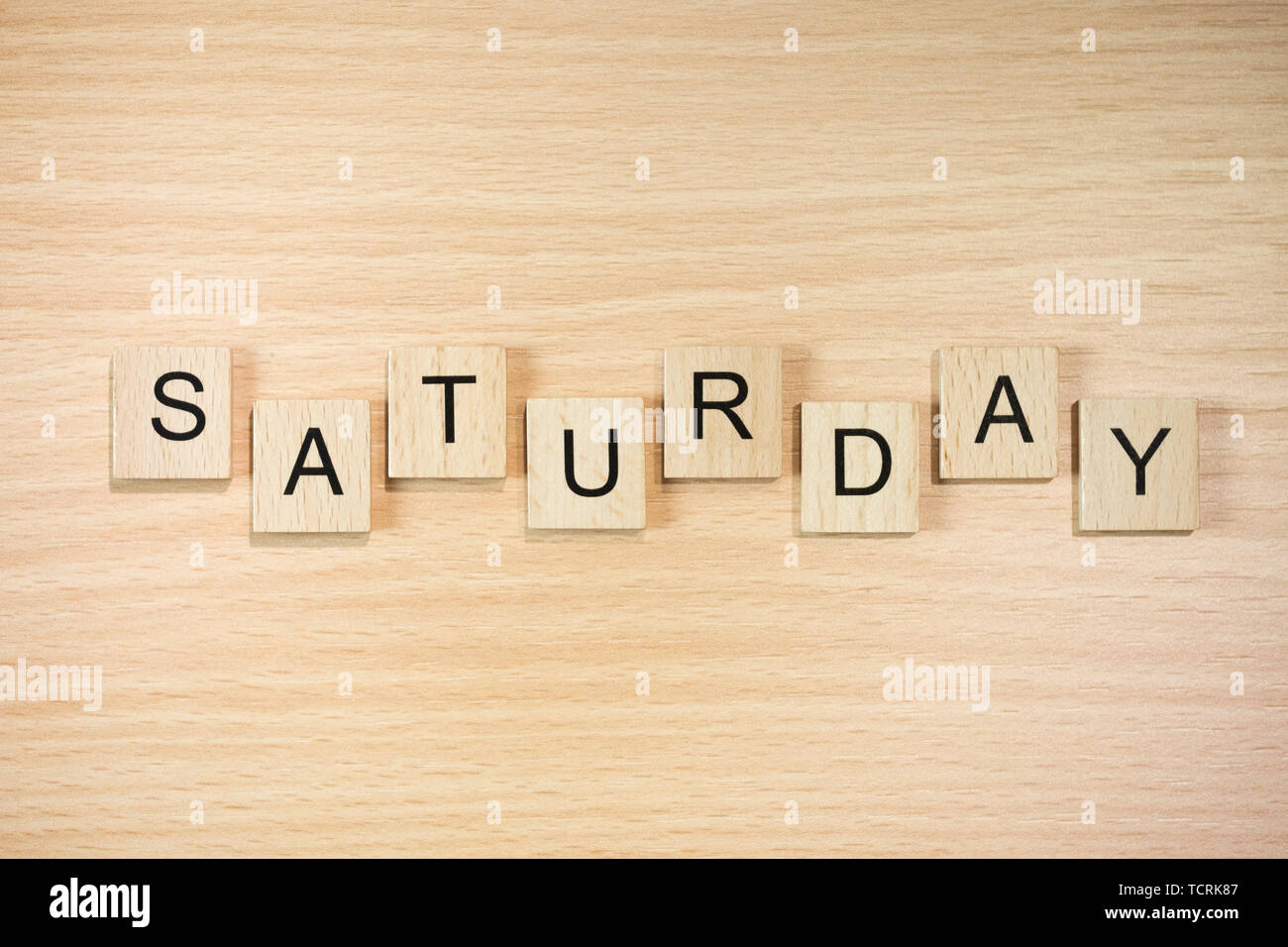 The word Saturday, spelt out using wooden tiles on a wood effect ...