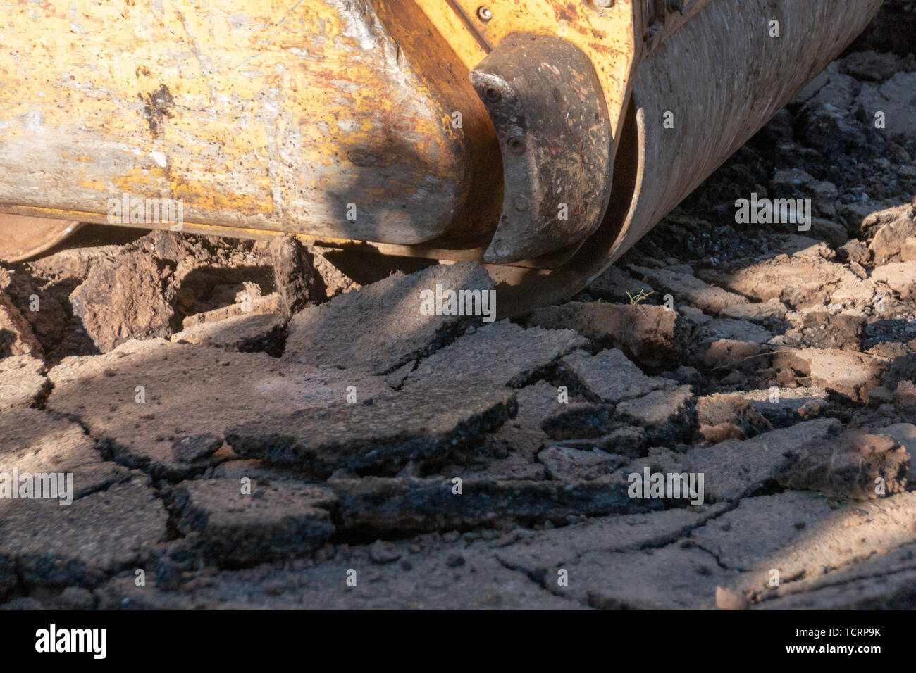 A close up view of a tar rolling machine smoothing out the crusher take ...