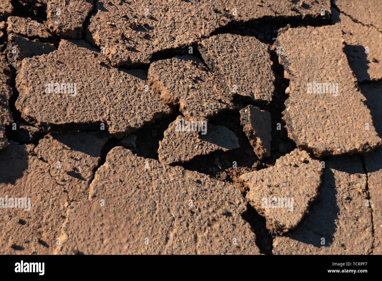 A close up view of an old driveway where the tar has been broken up ...