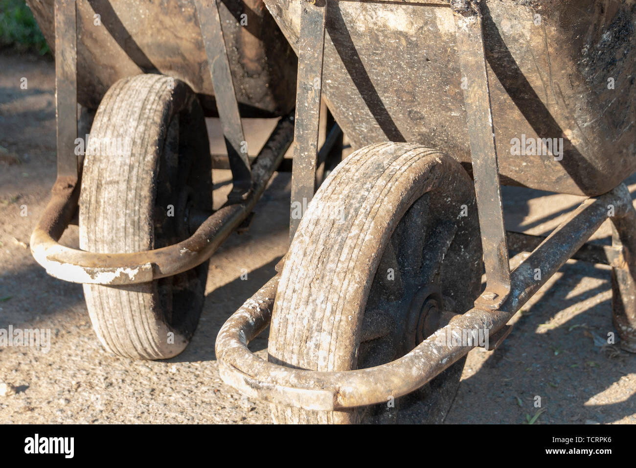 A close up view of the front bottom of two old work wheel barrows Stock ...