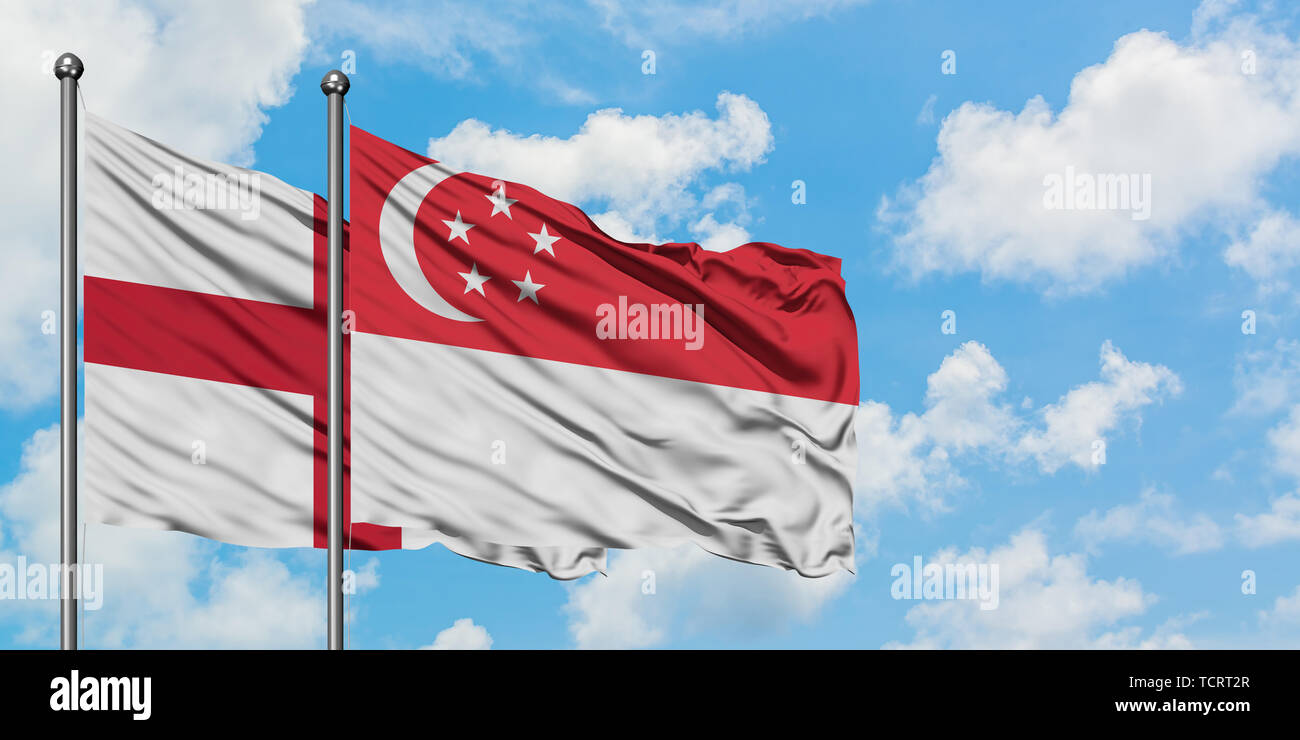 England and Singapore flag waving in the wind against white cloudy blue ...
