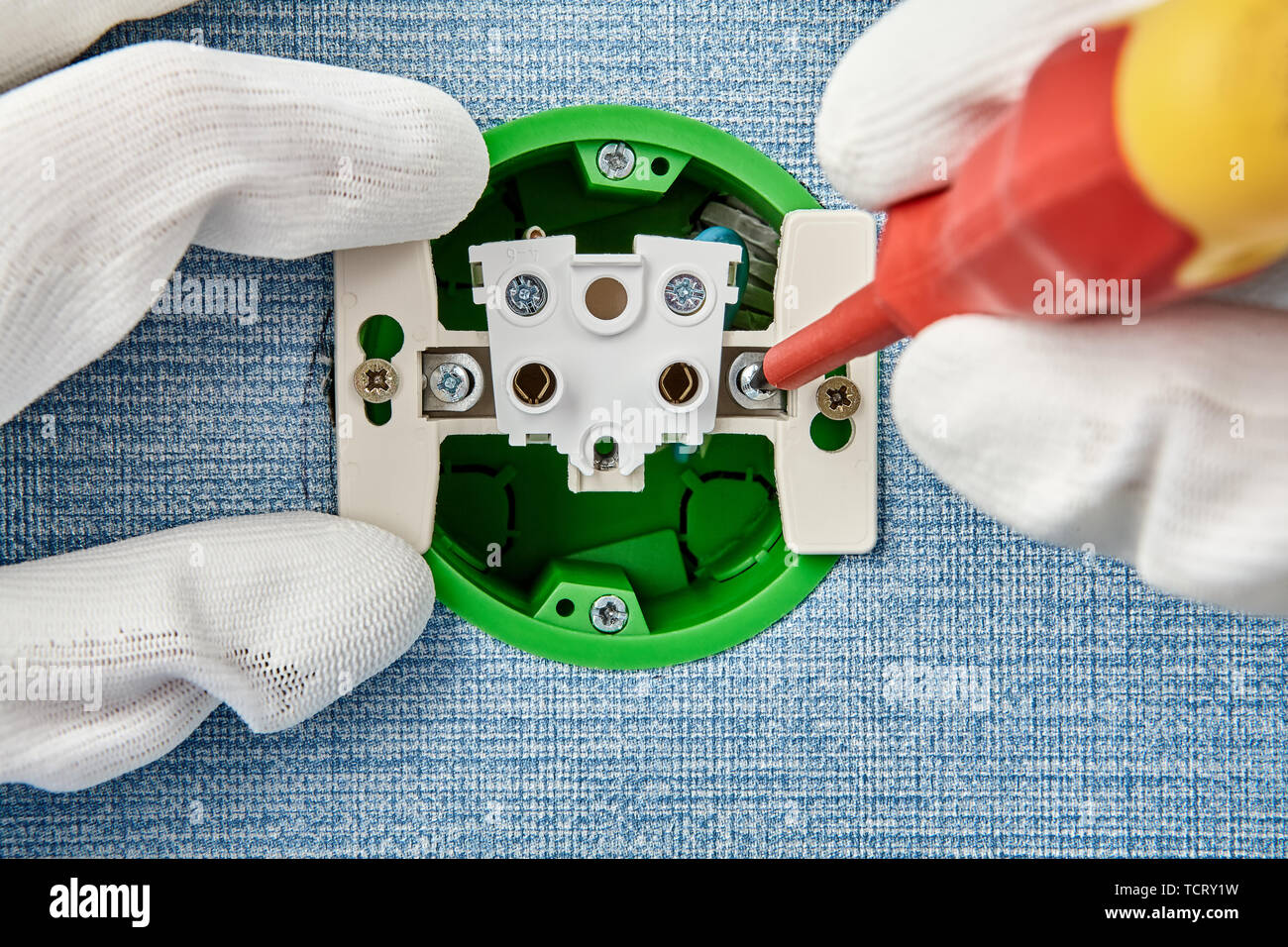 Technician is installing electrical socket in home electrical wiring ...