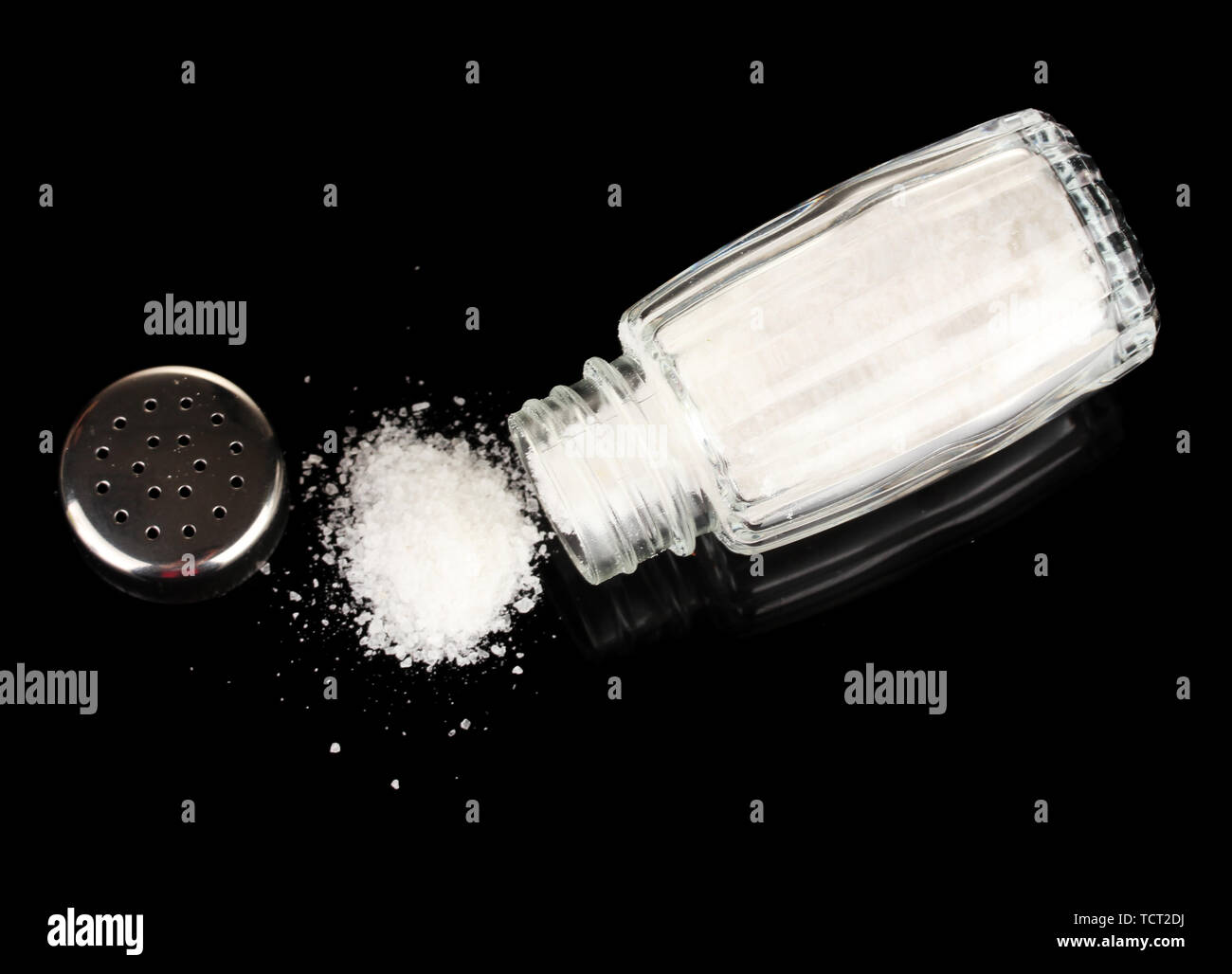 Salt shaker with spilled salt isolated on black Stock Photo - Alamy