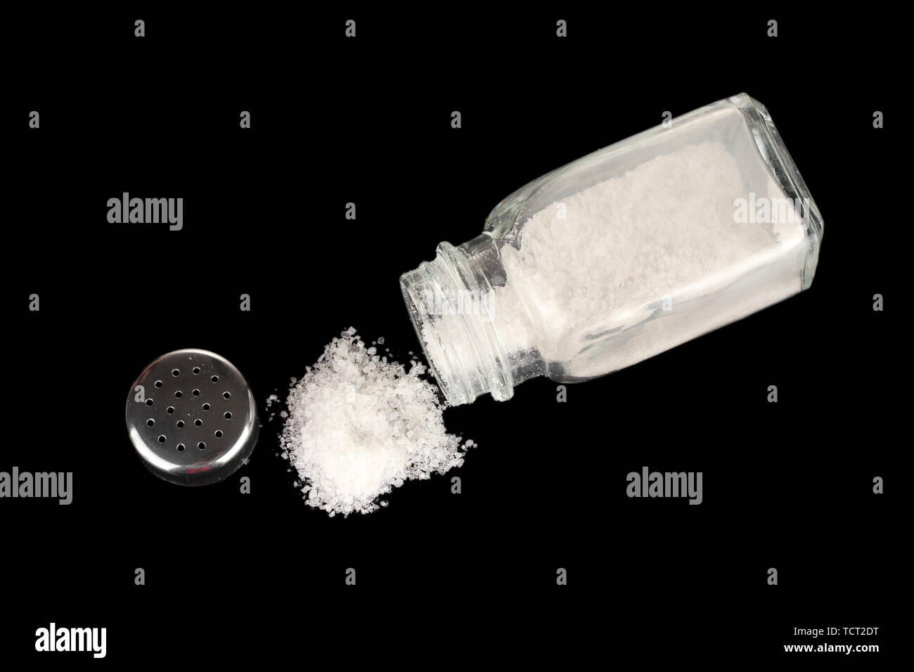 Salt shaker with spilled salt isolated on black Stock Photo - Alamy