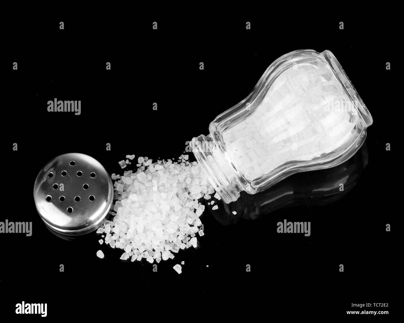 Salt shaker with spilled salt isolated on black Stock Photo - Alamy