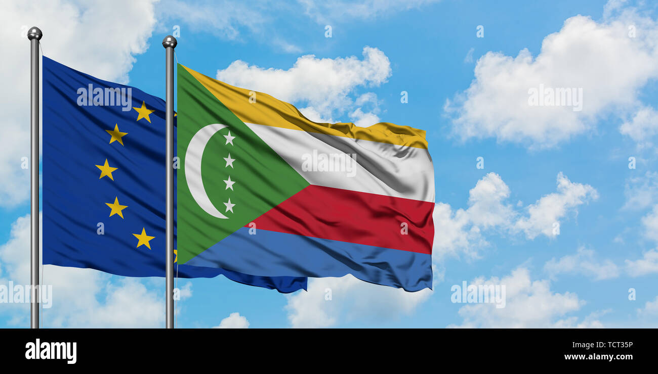 European Union and Comoros flag waving in the wind against white cloudy ...