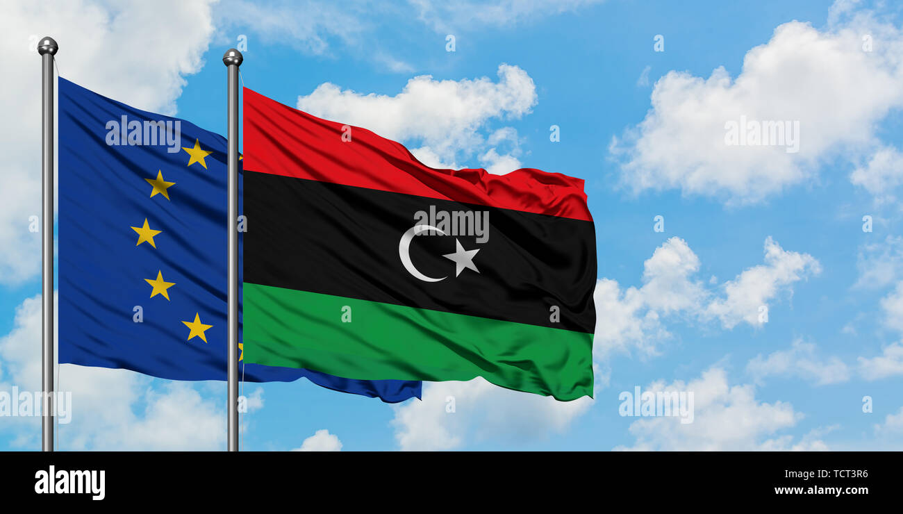 European Union and Libya flag waving in the wind against white cloudy ...