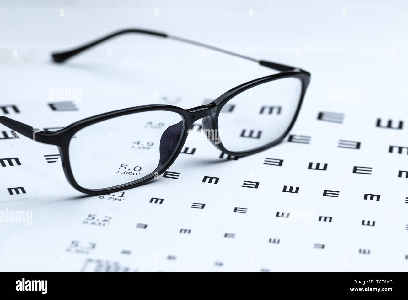 Glasses and eye chart on white background Stock Photo - Alamy