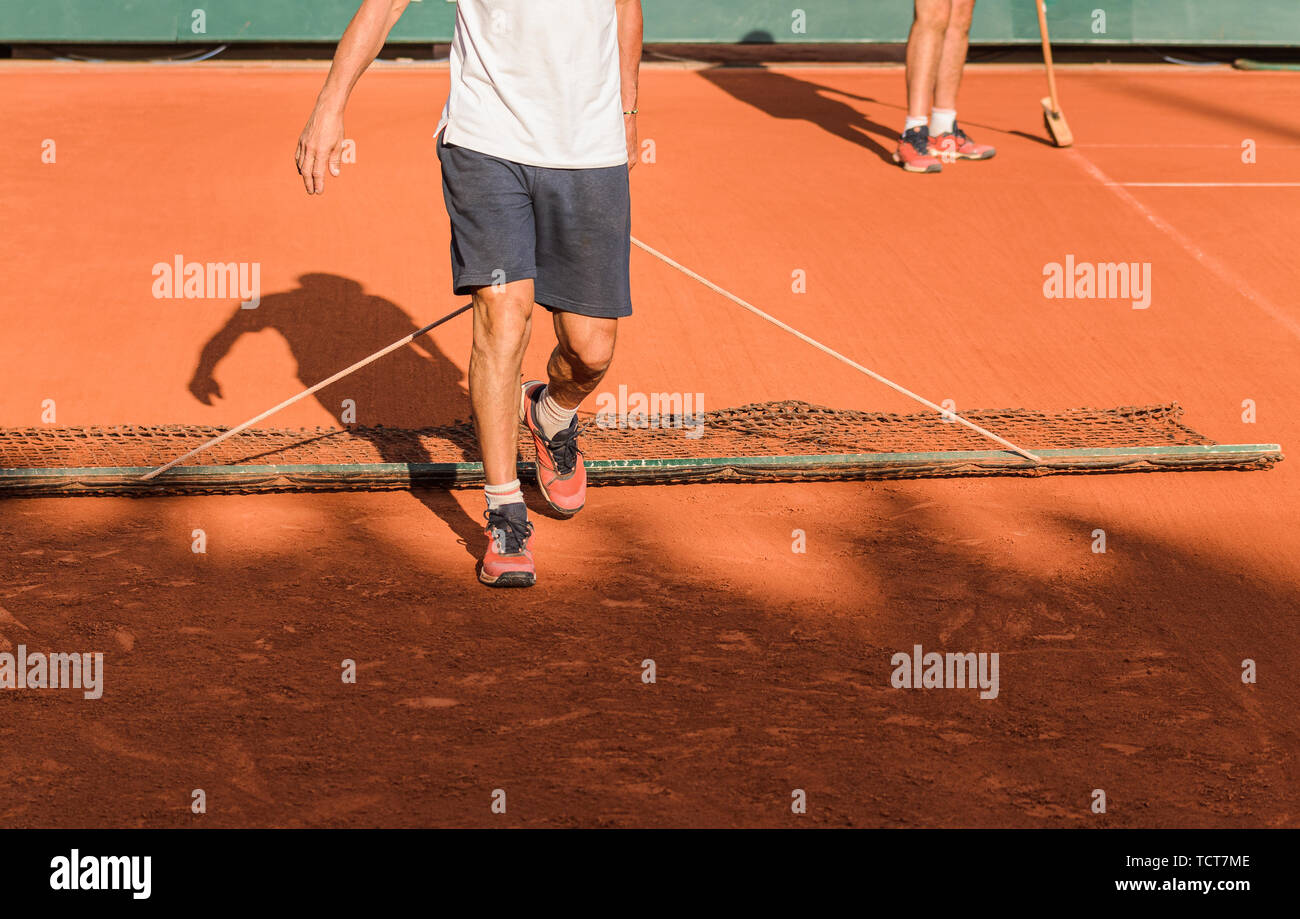 Two men clean tennis clay court. Cleaning of the ground and lines for ...