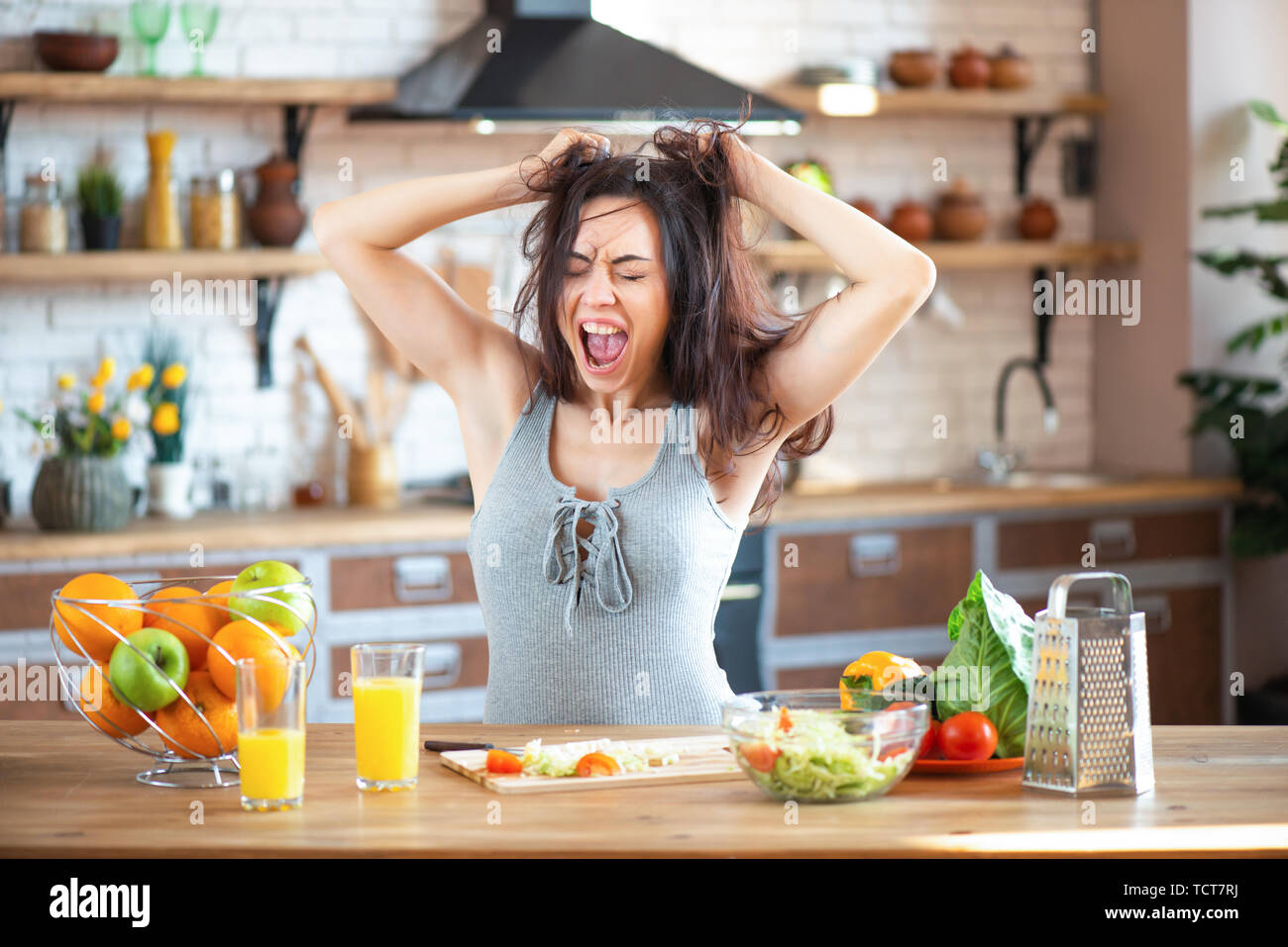 Female tantrum in the kitchen. A young girl grunts and tears her hair ...