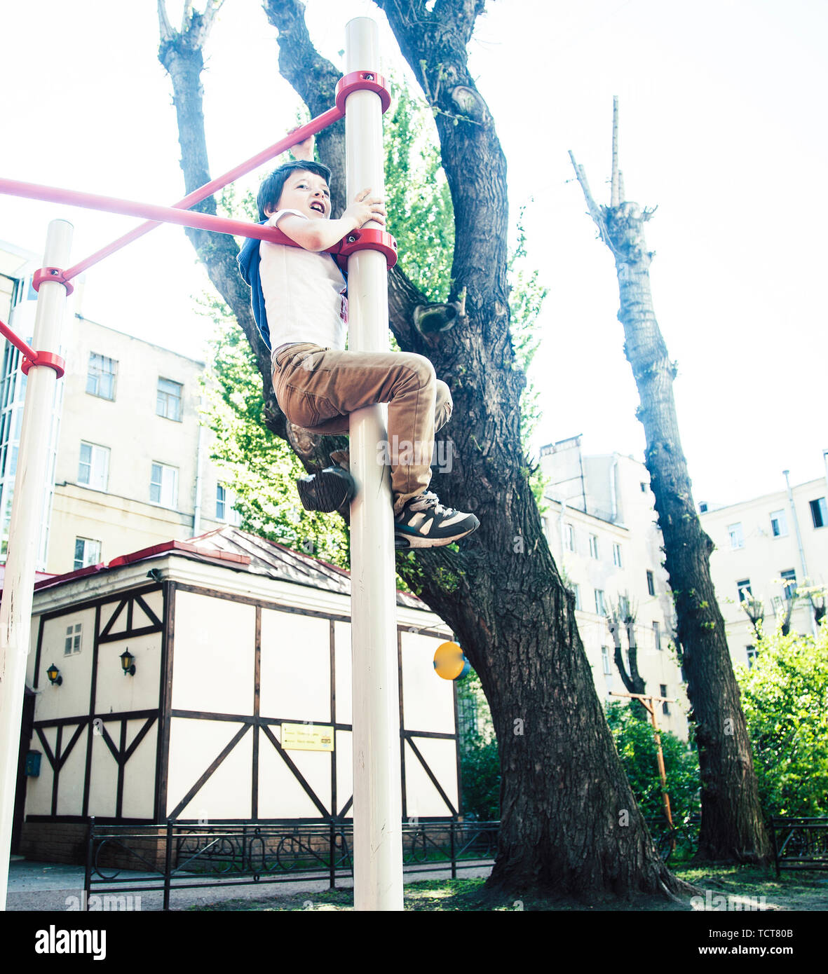 little cute blond boy hanging on playground outside, alone training ...
