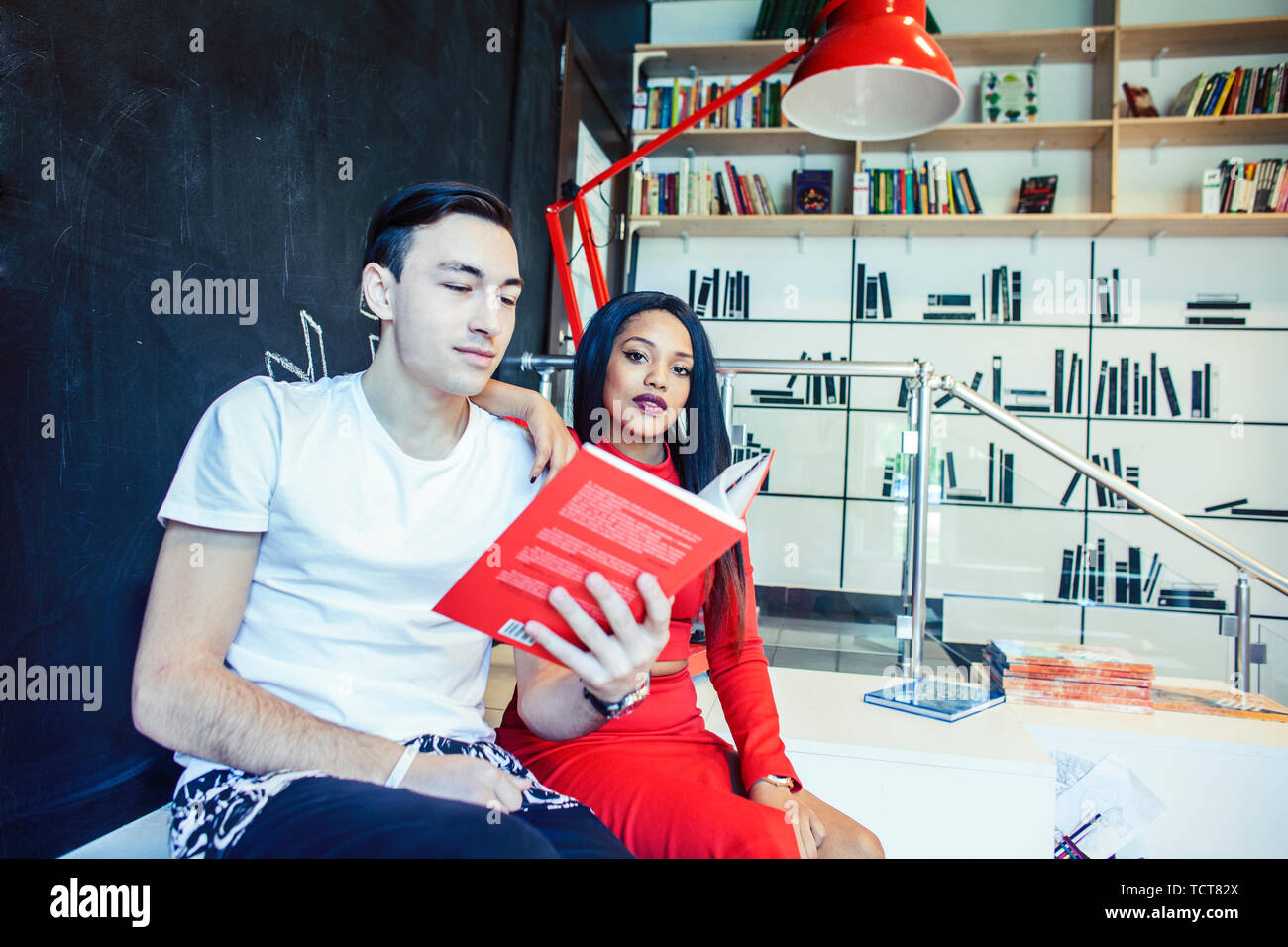couple students in univercity library, looking book, preparing to exam ...