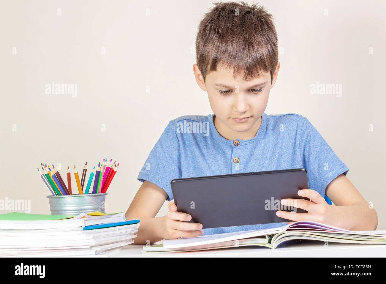 Kid with tablet computer sitting at table with books notebooks Stock ...