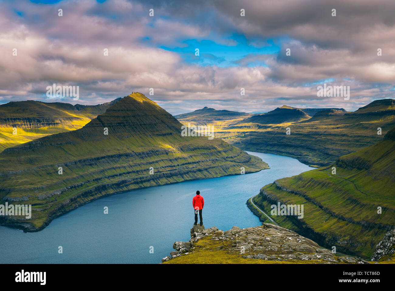 Hiker enjoys views over fjords from a mountain near Funningur on Faroe ...