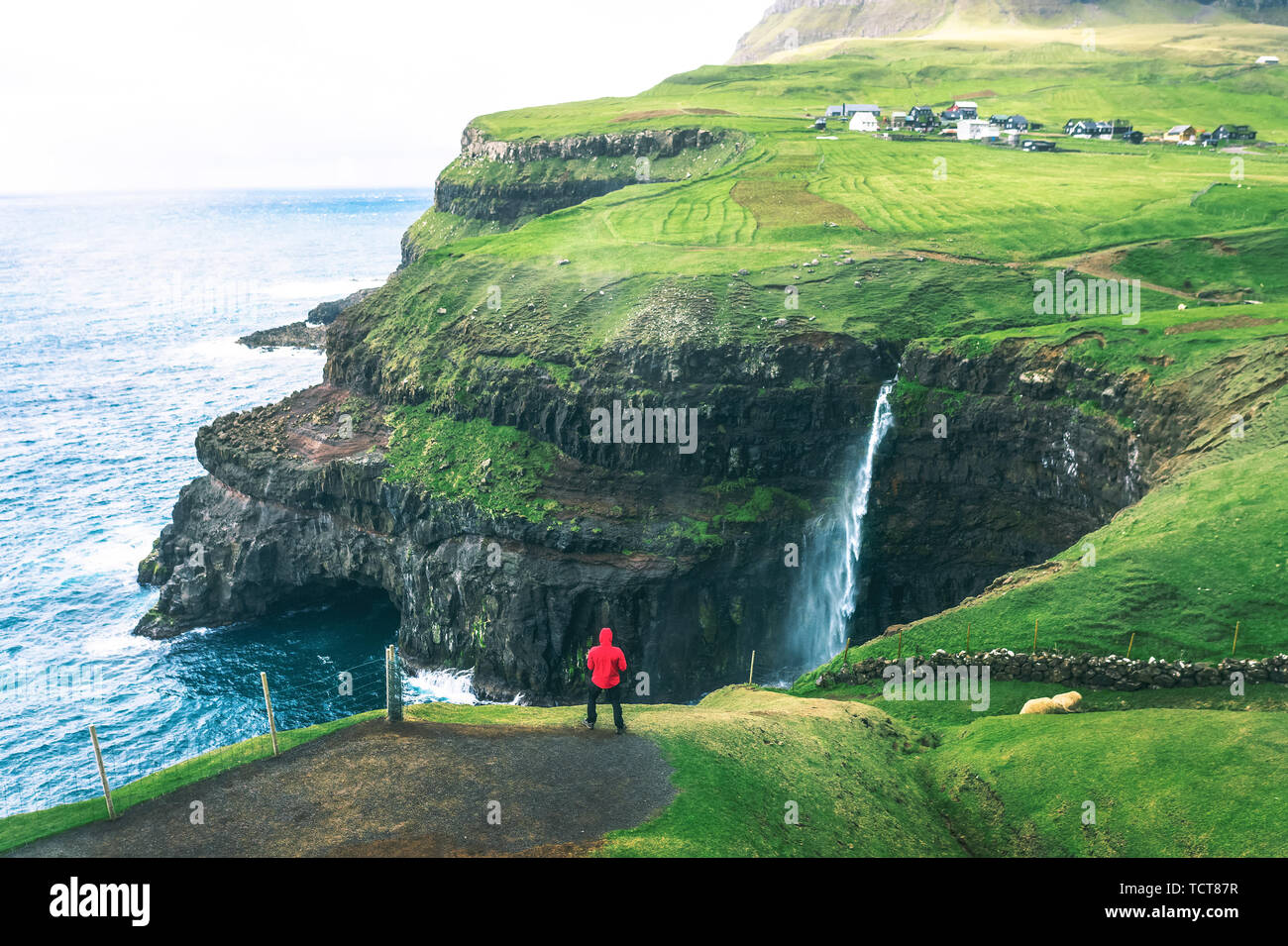 Tourist looks at the Mulafossur waterfall near Gasadalur on Faroe ...