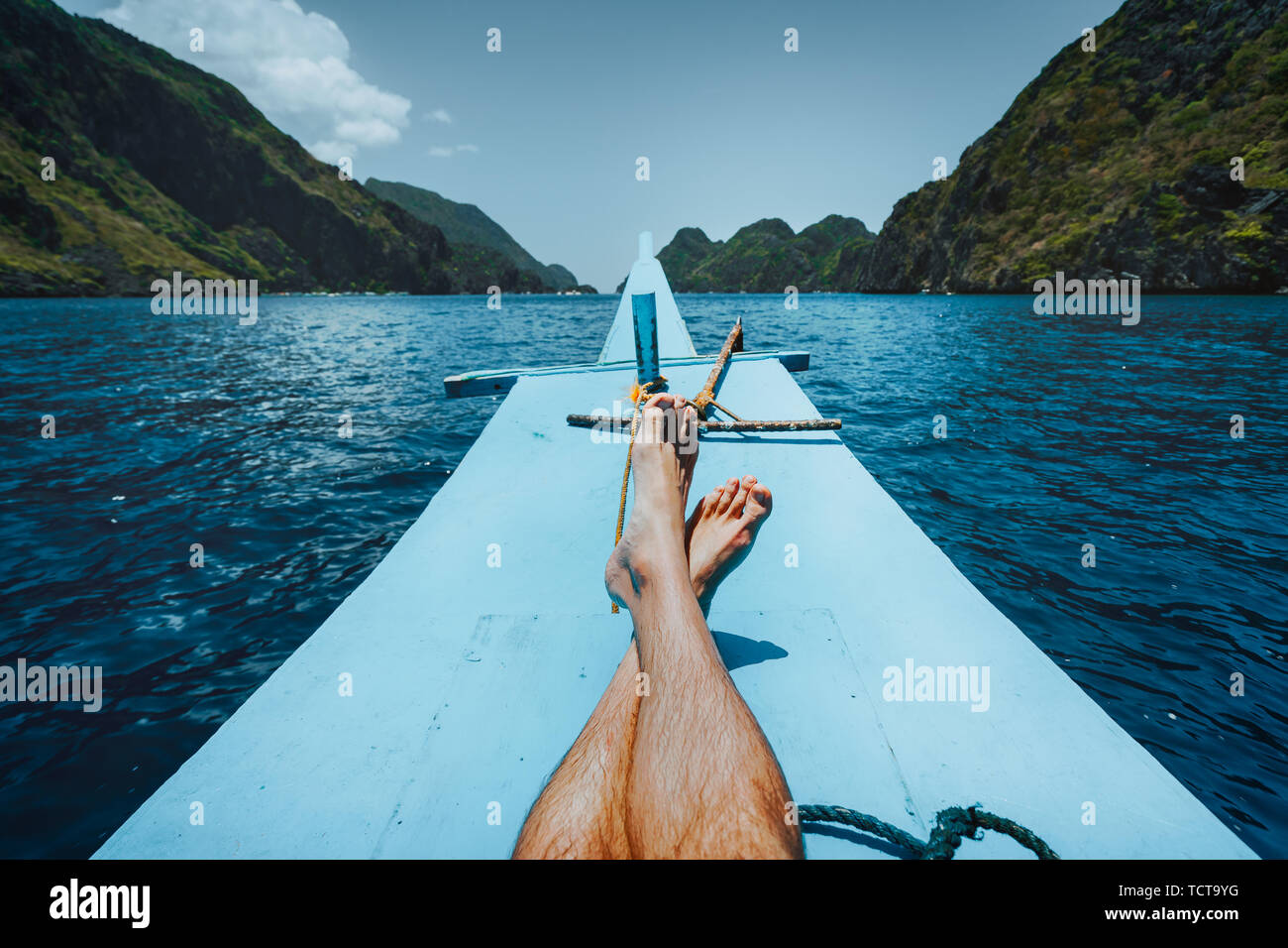 Legs of man on banca boat approaching tropical island. travel ...