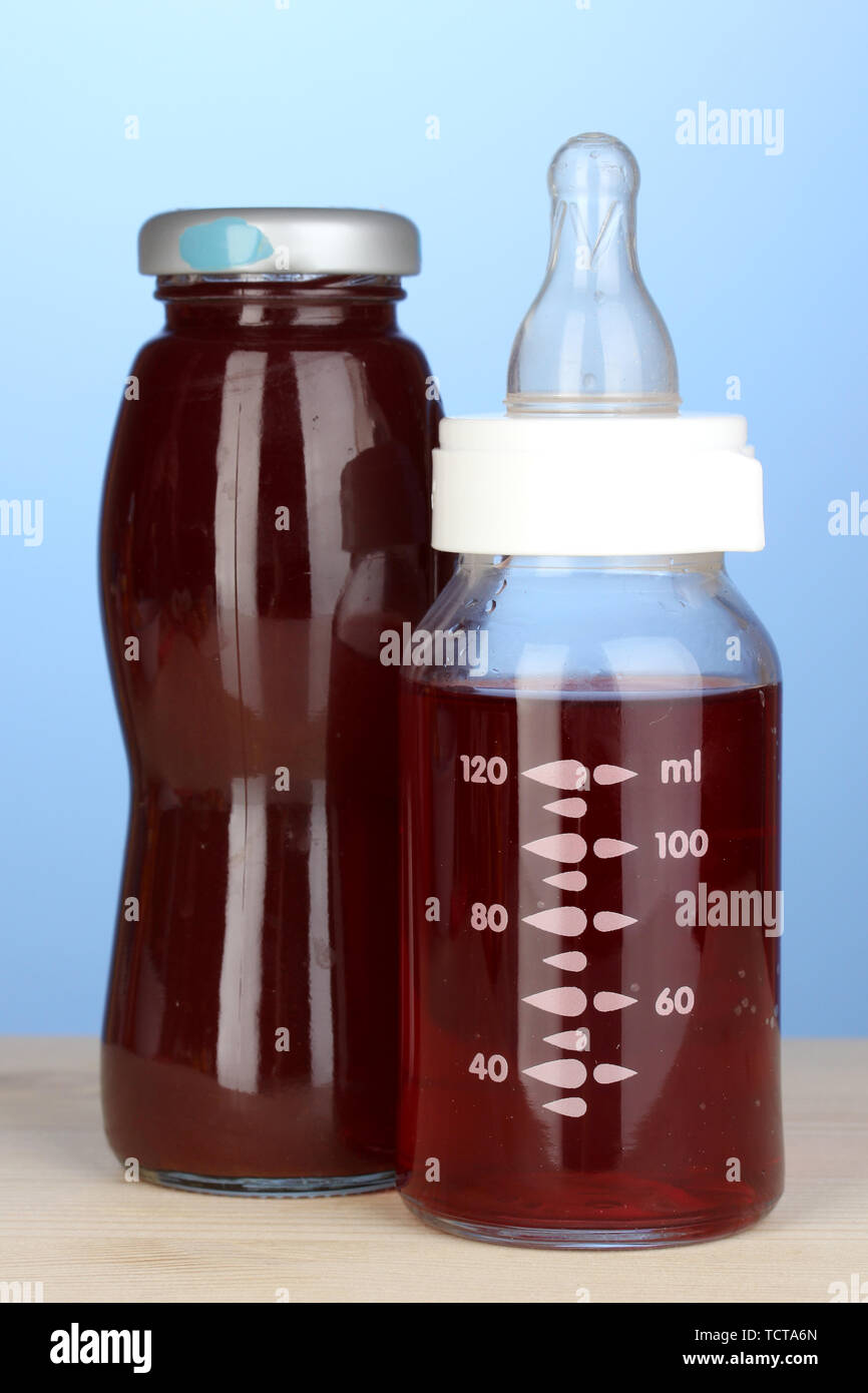 Baby bottle with fresh juice on blue background Stock Photo - Alamy