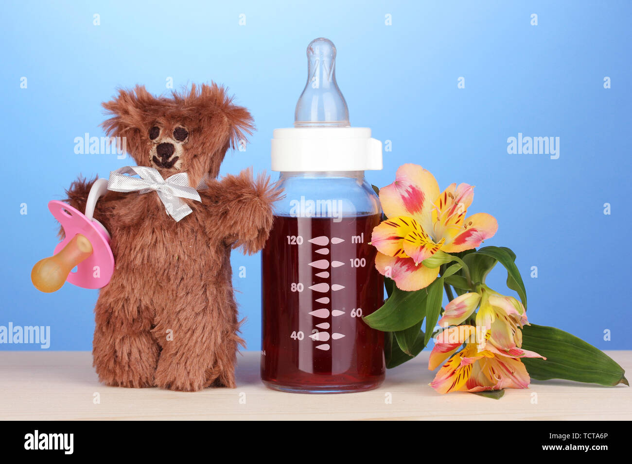 Baby bottle with fresh juice and teddy bear on blue background Stock ...