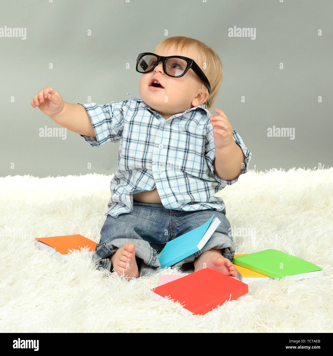 Little boy with multicolor books, on white carpet Stock Photo - Alamy