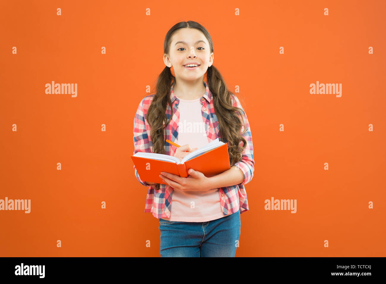 Dig into reading. Cute small child reading a book on orange background ...