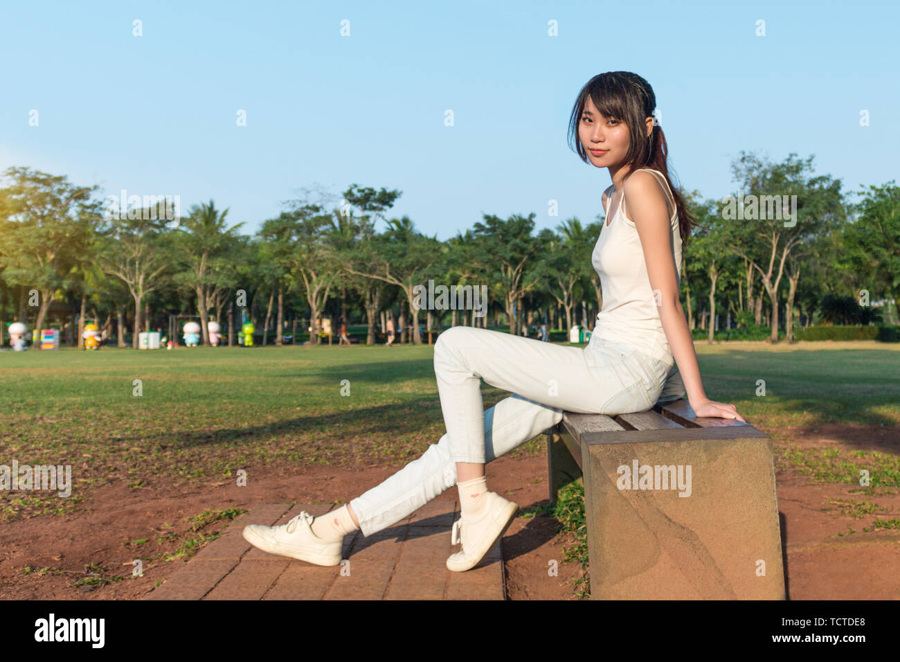 A girl sitting in the sun on a park bench Stock Photo - Alamy